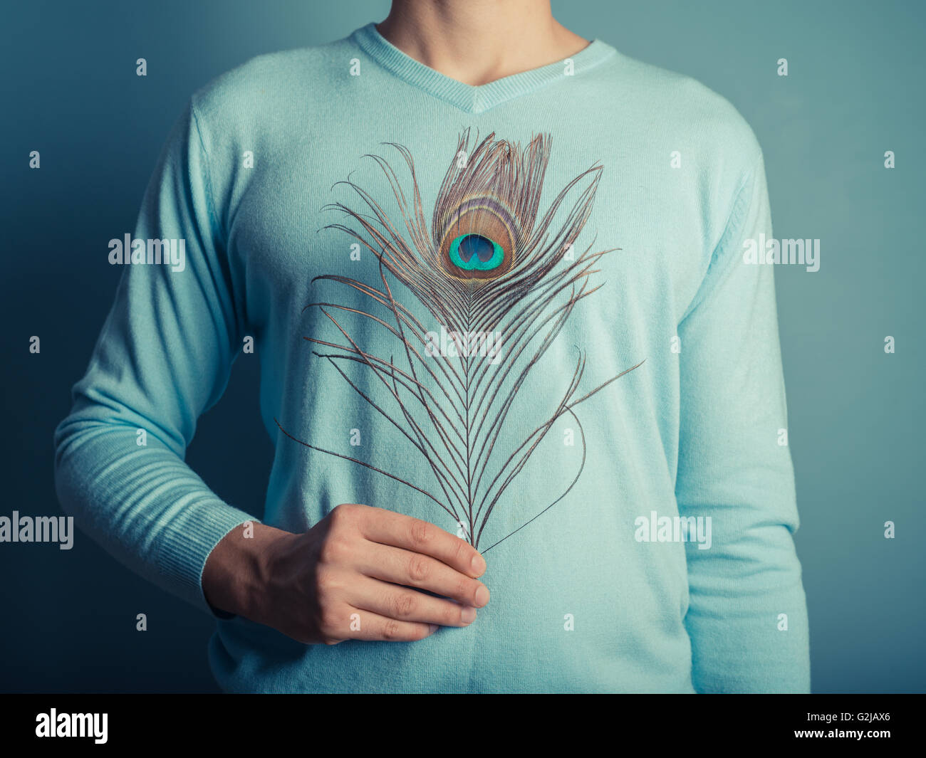 A young man is holding a pretty peacock feather Stock Photo - Alamy