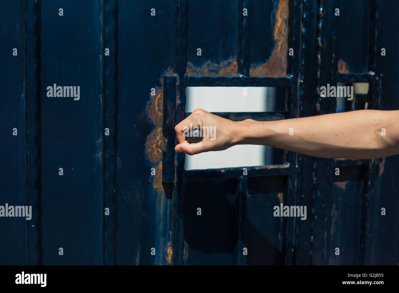 A young female hand is grapping the hand handle of a gate and is ...