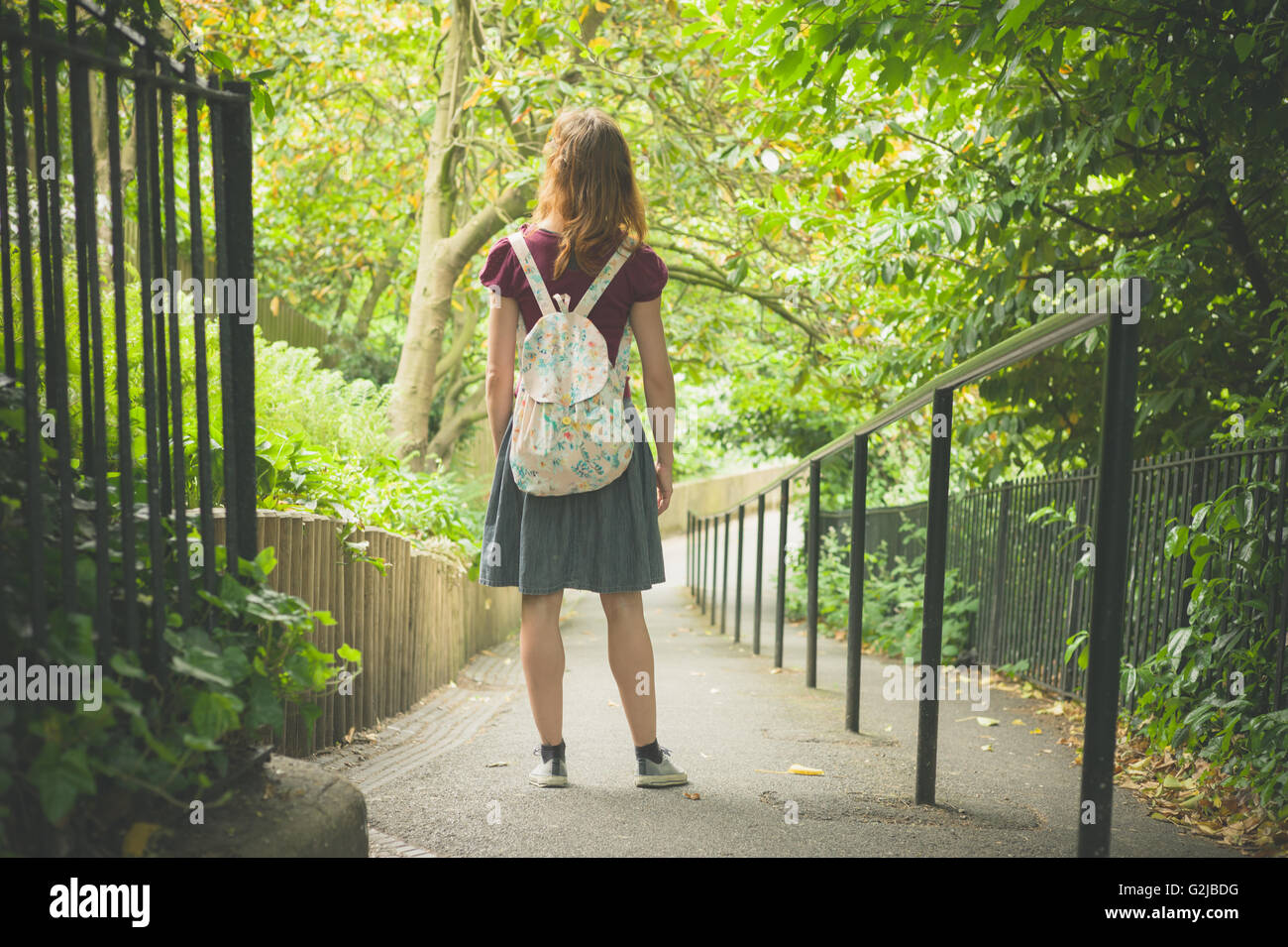 A young woman is standing by a railing in a forest Stock Photo - Alamy