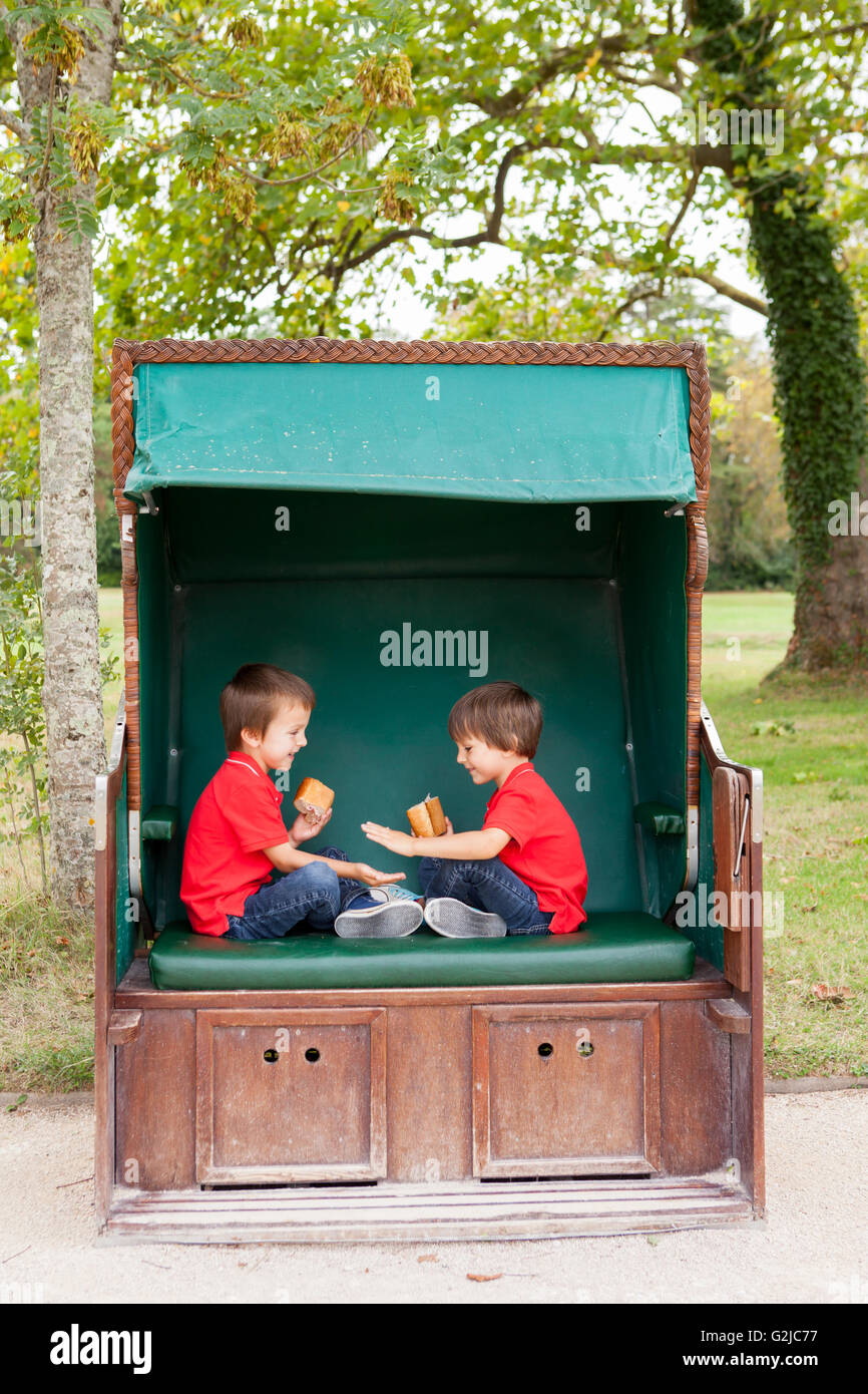 Two kids, sitting in a sheltered bench, playing hand clapping game and ...