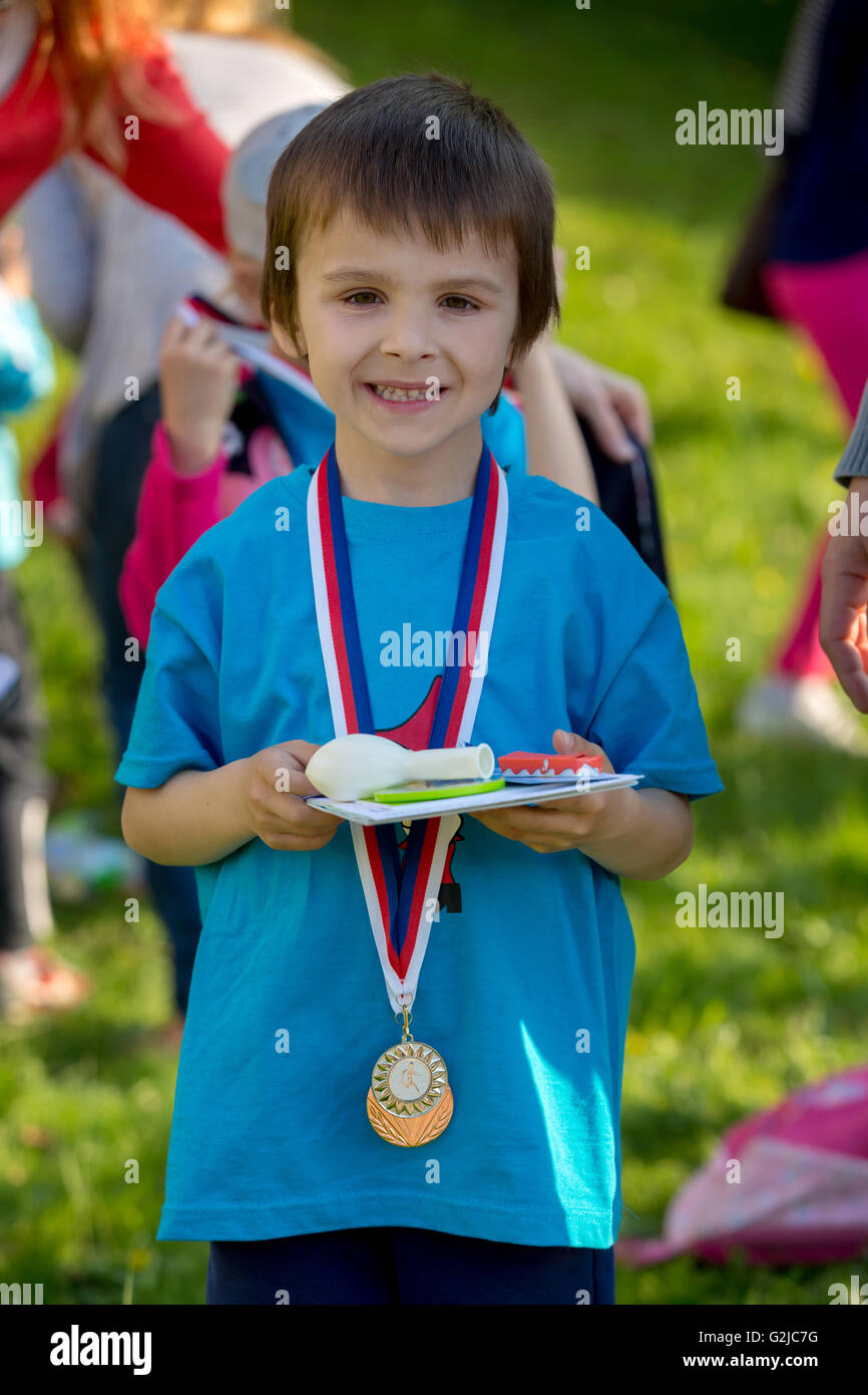 Proud preschool boy, holding prizes and medals after annual sport ...