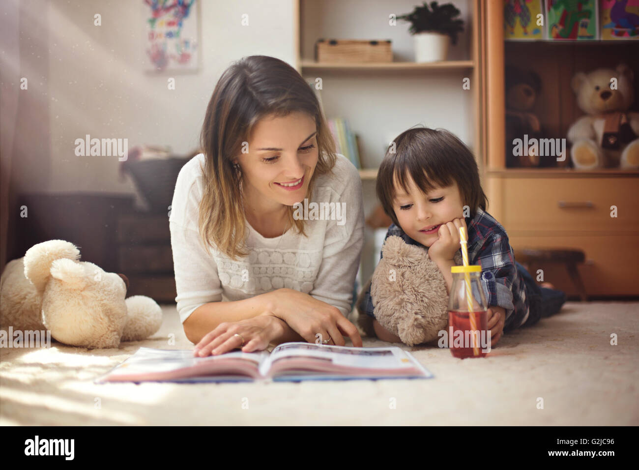Young mother, read a book to her tho children, boys, in the living room ...