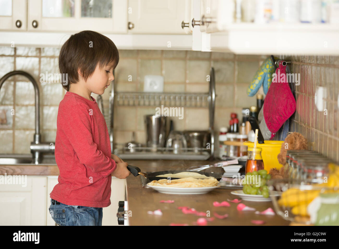 Sweet preschool child, helping his mom in the kitchen, making pancakes ...