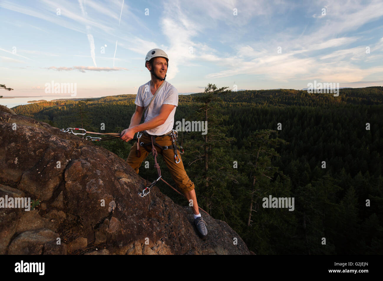 A male climber on Sunset Slab sets up a belay station while climbing on ...