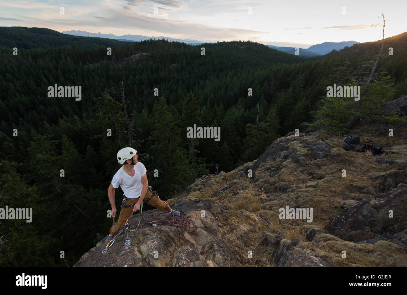 A male climber on Sunset Slab sets up a belay station while climbing on ...