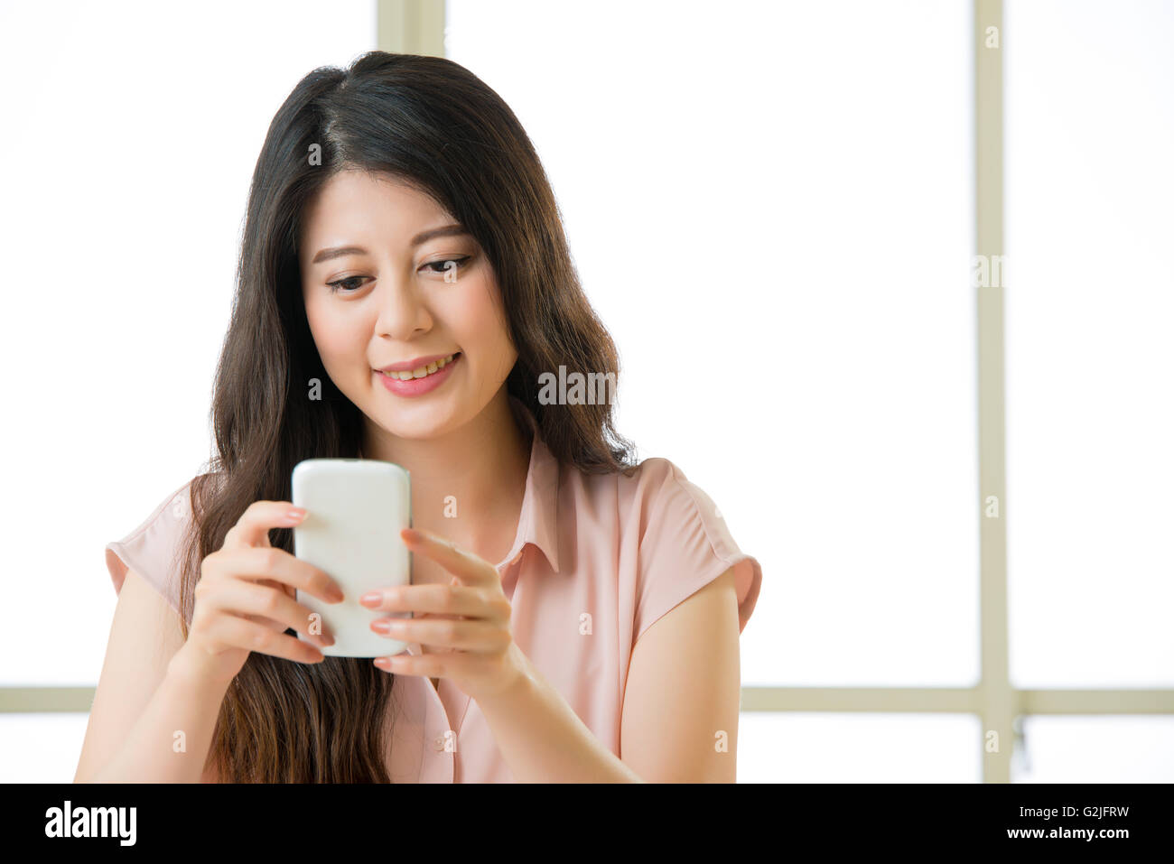 Happy young Asian woman using smart phone text messaging, working at ...