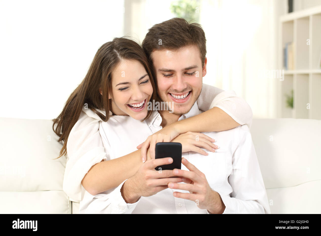 Funny couple or marriage sharing a smart phone to watch media content ...