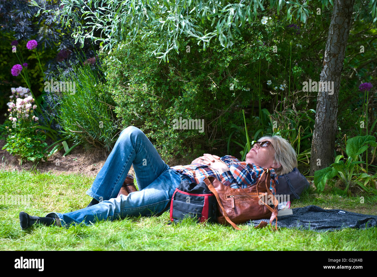 Woman sleeping in the shade of a tree on the lawn at Hay Festival 2016 ...