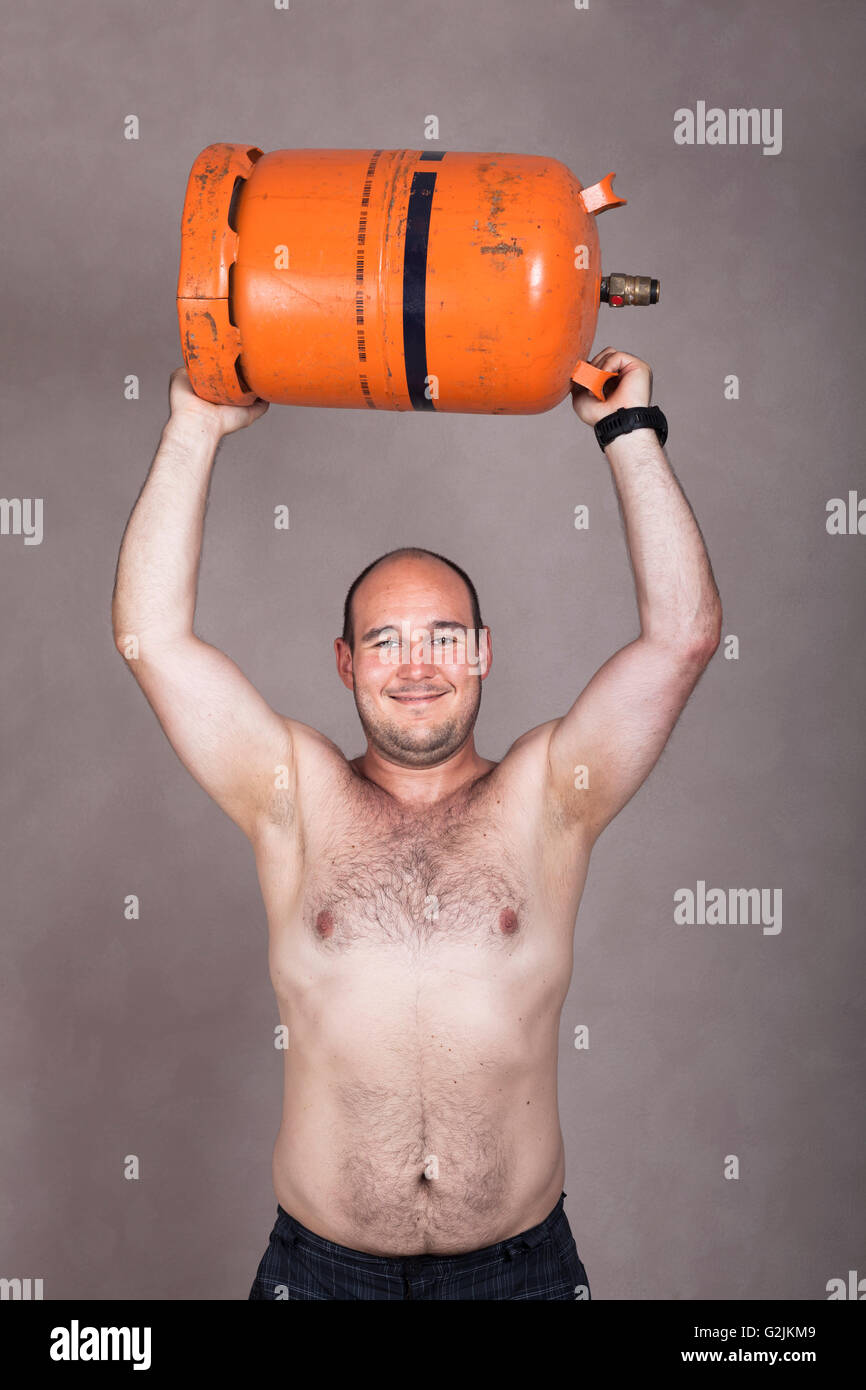 Portrait of happy strong shirtless worker man lifting heavy gas bottle ...