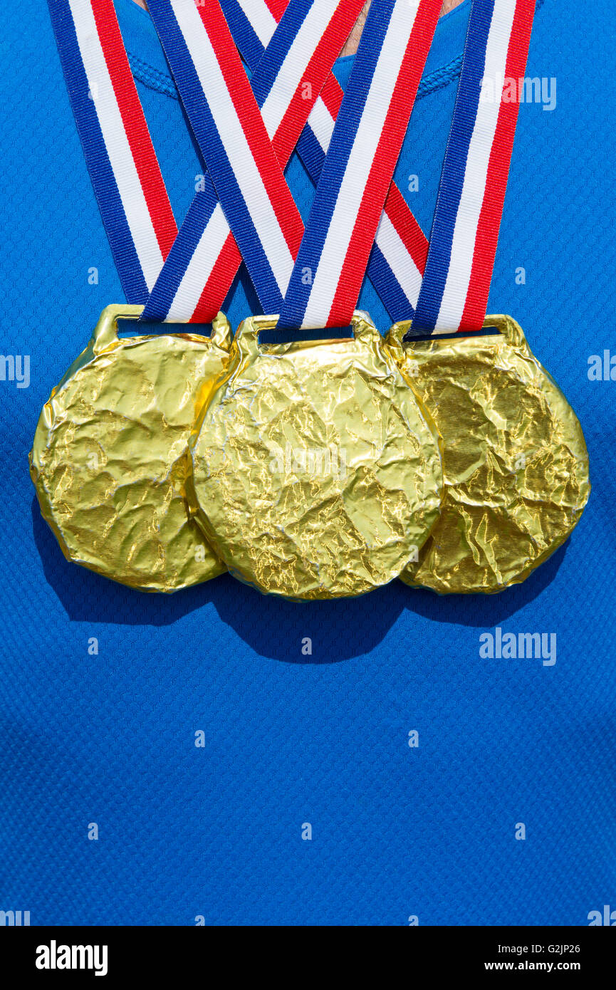 Gold medals hanging from USA colors red, white, and blue ribbon on blue ...