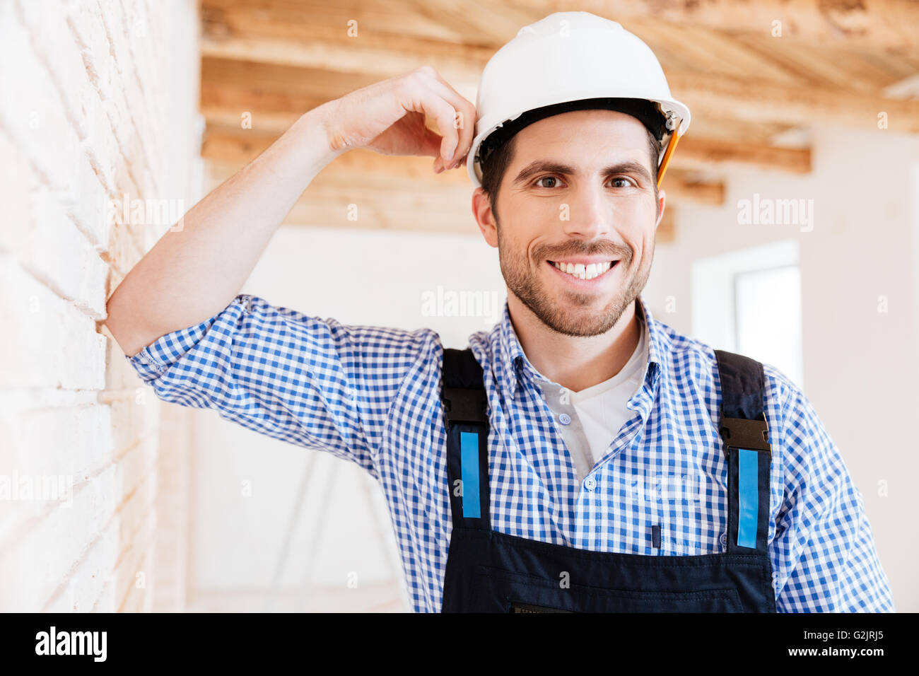 Smiling handsome builder standing near the wall in a new building Stock ...
