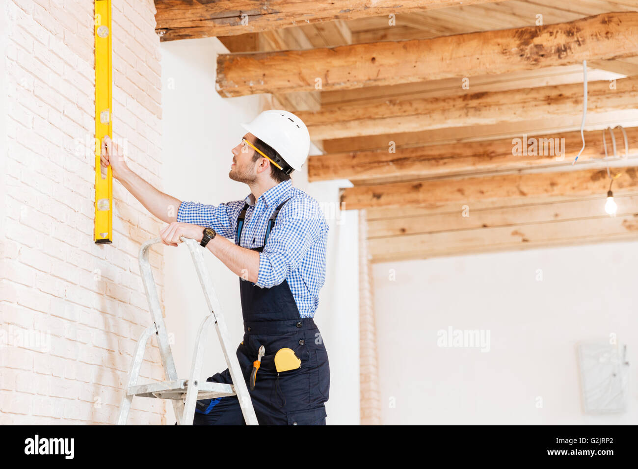 Builder using consruction level and standing n the ladder at the ...