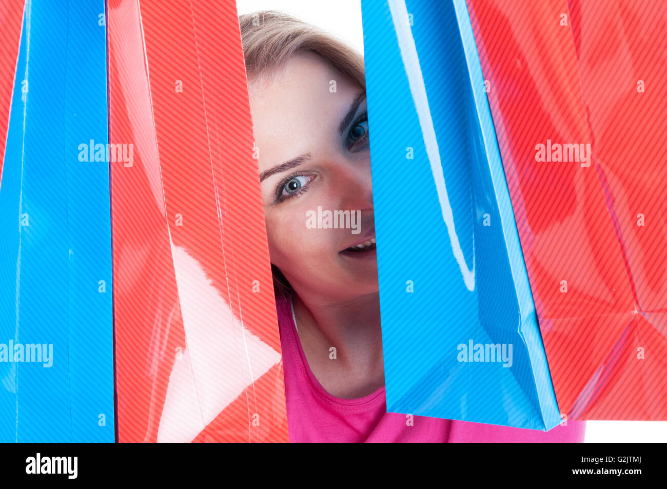Young happy smiling woman hiding behind colored paper bags acting ...