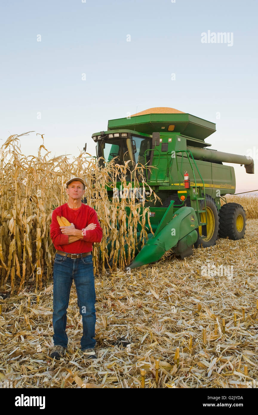 a man next to a combine harvester filled with the harvested crop near ...