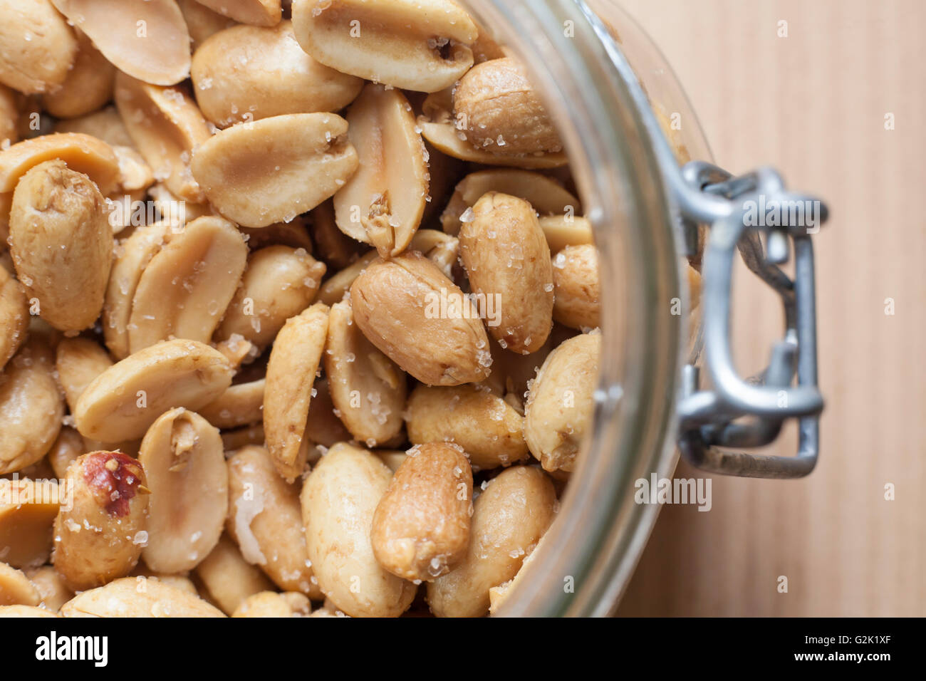 Open canning jar with fried salty peanuts. Selective focus. High angle ...
