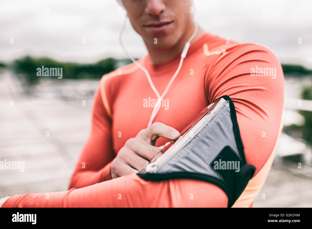 Runner man tuning his mp3 music player during jogging Stock Photo - Alamy