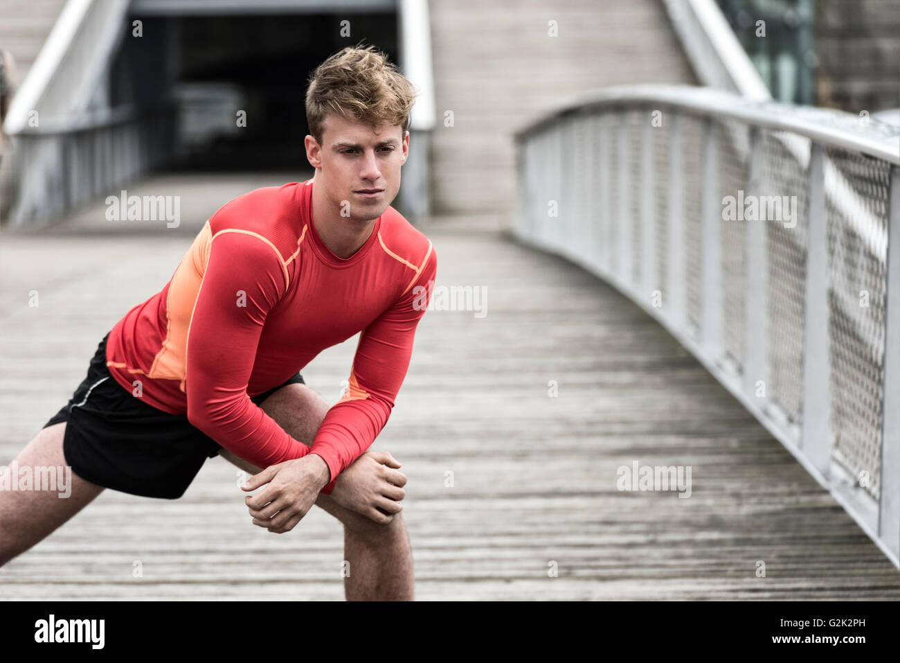Athletic young male stretching leg outside Stock Photo - Alamy