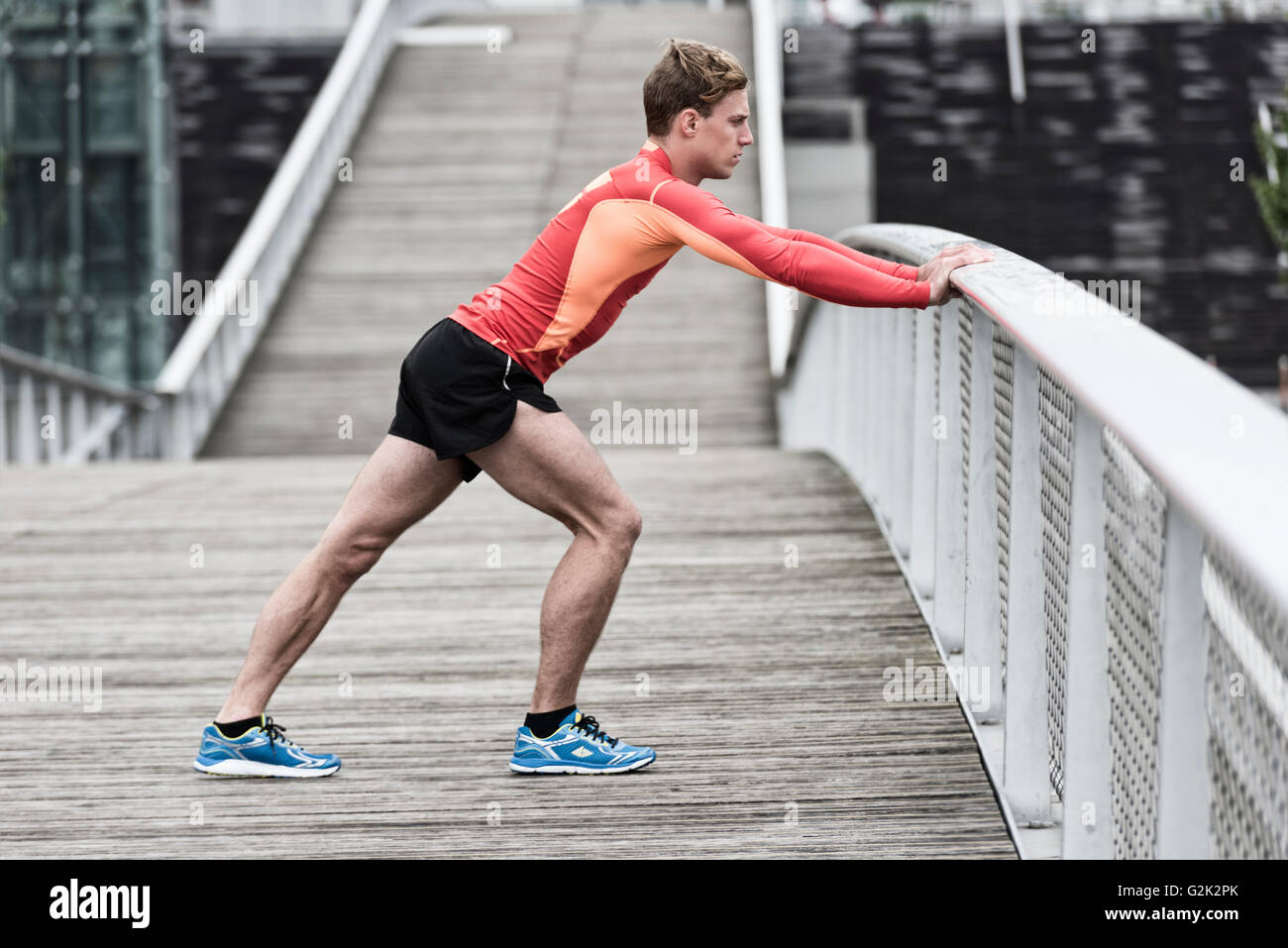 Athletic young male stretching leg outside Stock Photo - Alamy