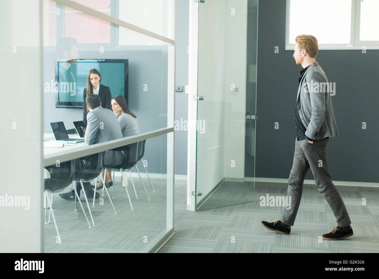 Young businessman walking through the modern office Stock Photo - Alamy