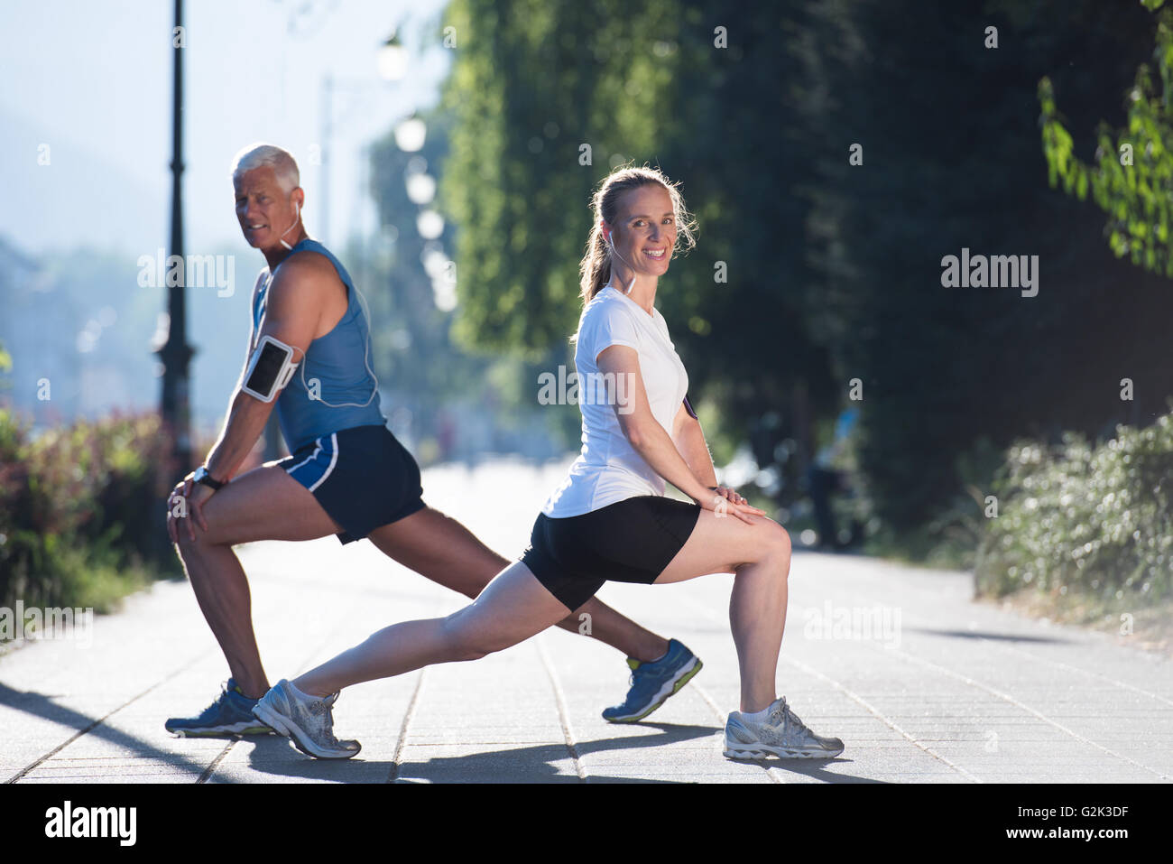 jogging couple warming up and stretching before morning running ...