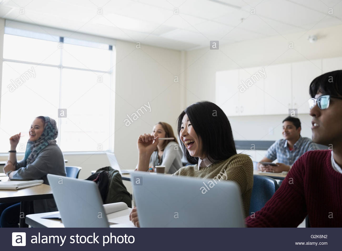 Laughing ESL student at laptop in classroom Stock Photo - Alamy