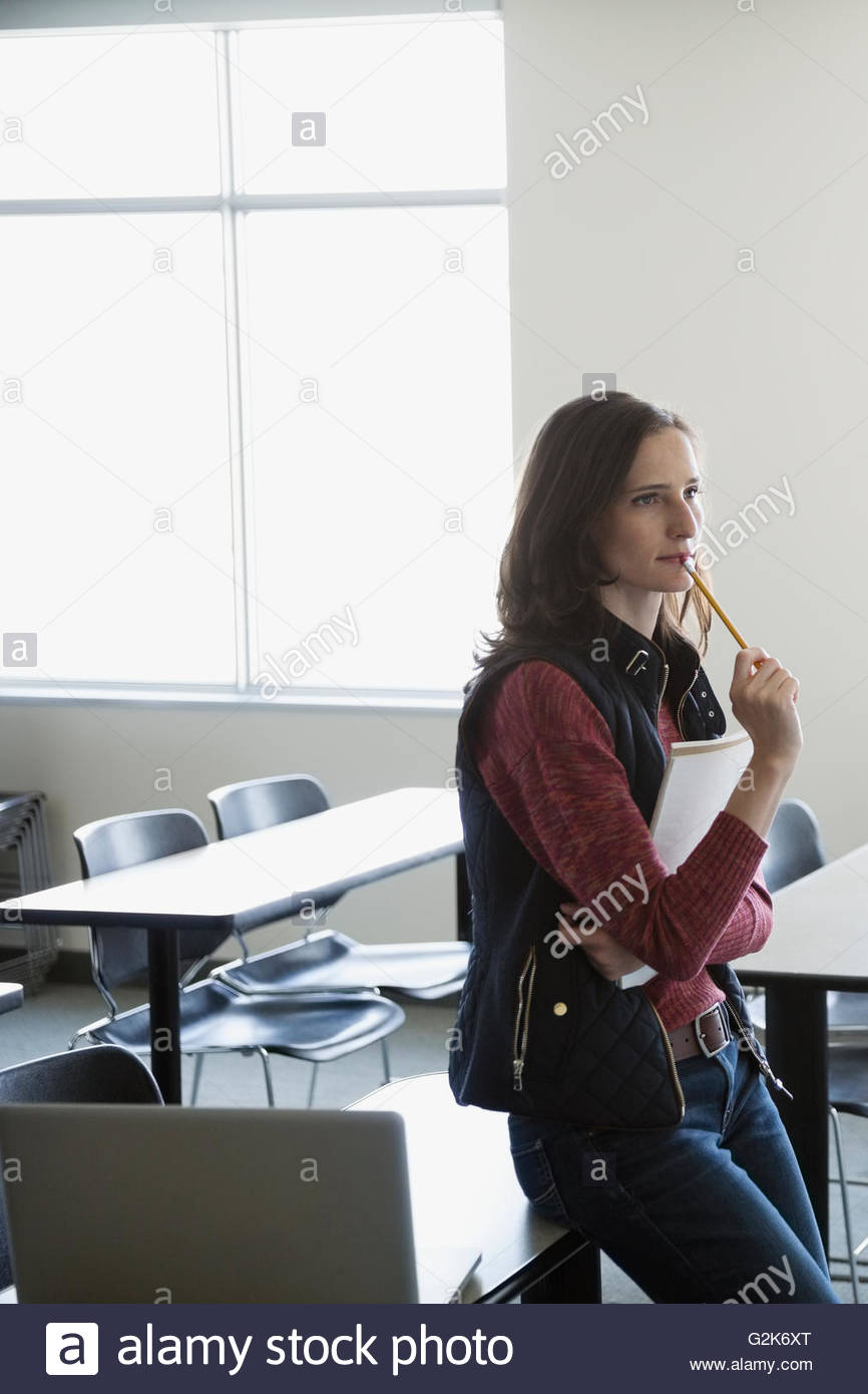 Pensive professor with laptop looking away in classroom Stock Photo - Alamy