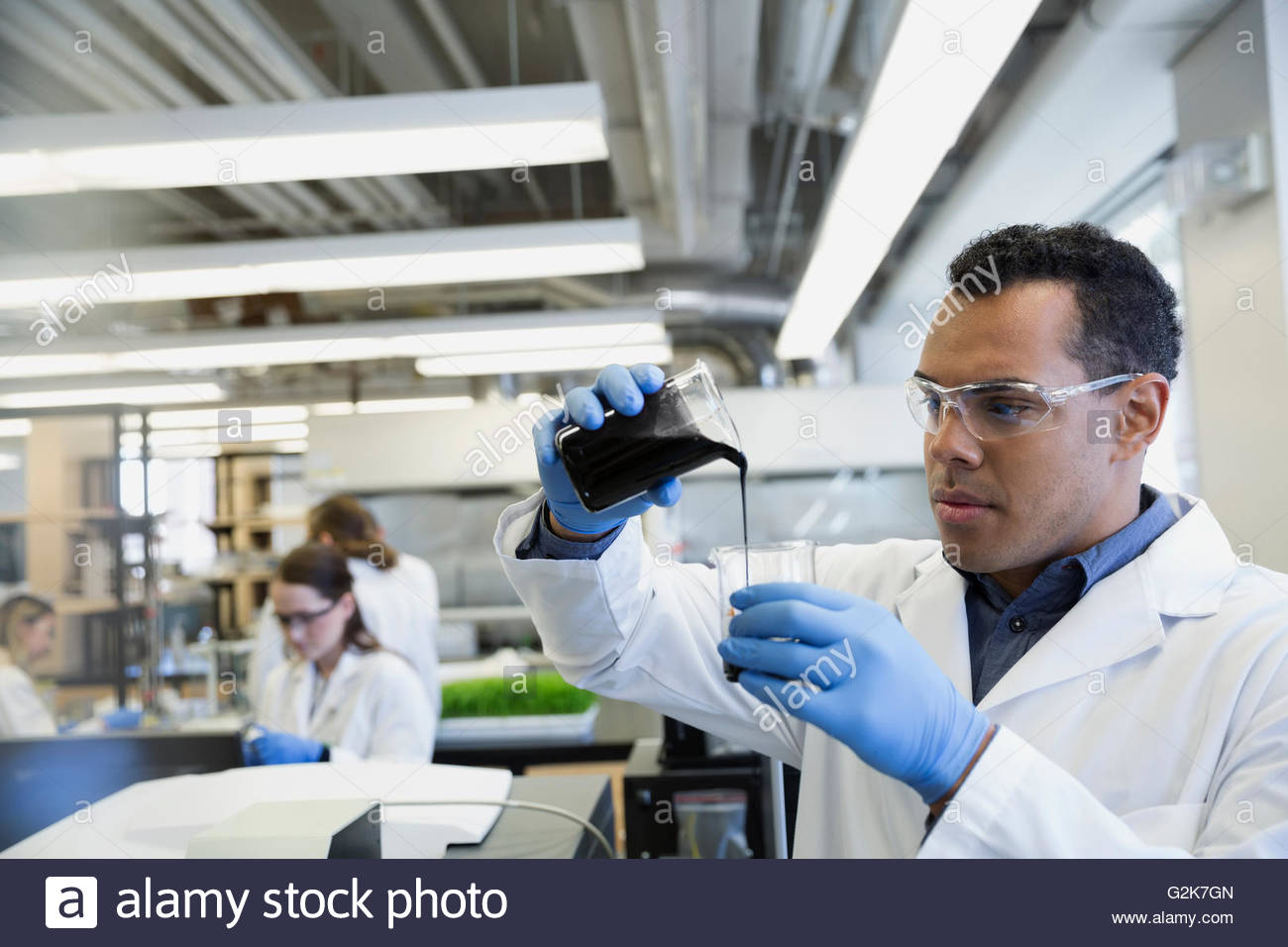 Scientist pouring liquid into beaker hi-res stock photography and ...