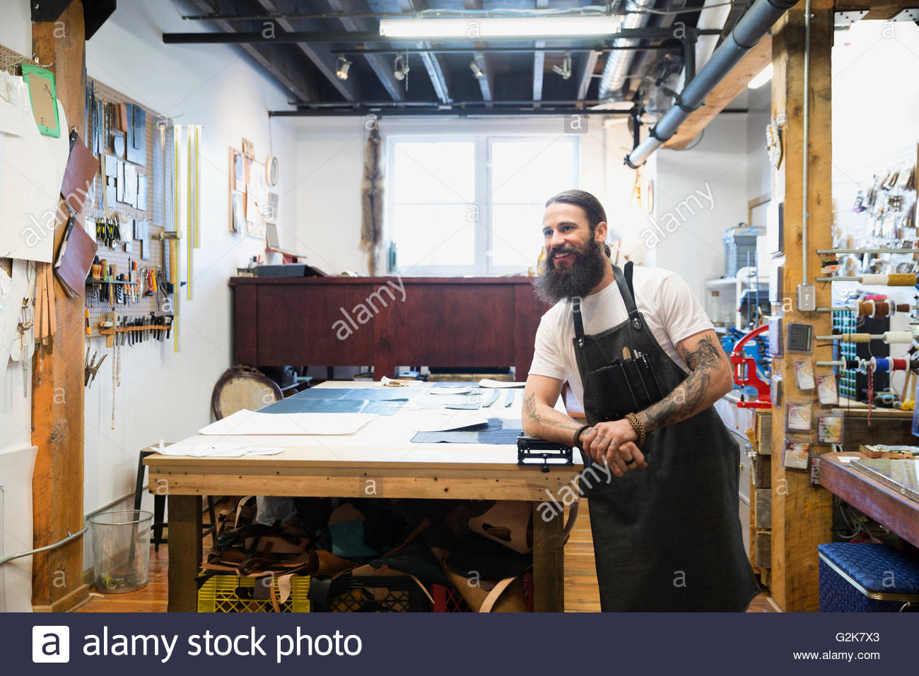 Smiling leather worker leaning on workbench Stock Photo - Alamy