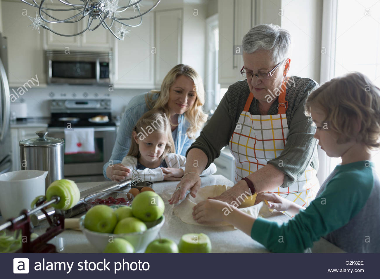 Multi-generation family baking apple pie in kitchen Stock Photo - Alamy