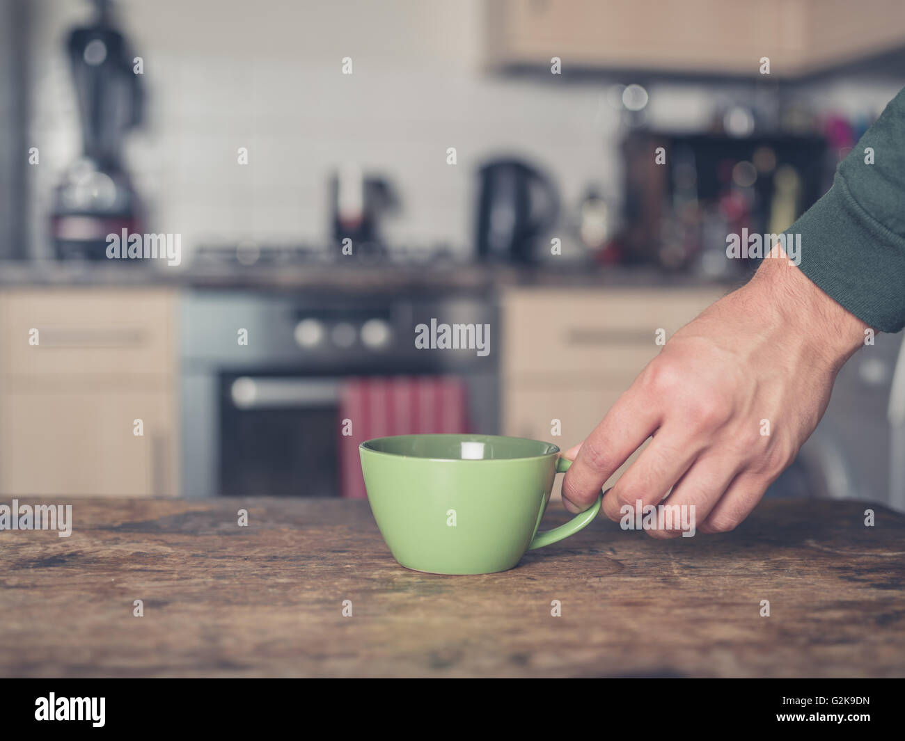 A male hand is placing a cup on a table in a kitchen Stock Photo - Alamy