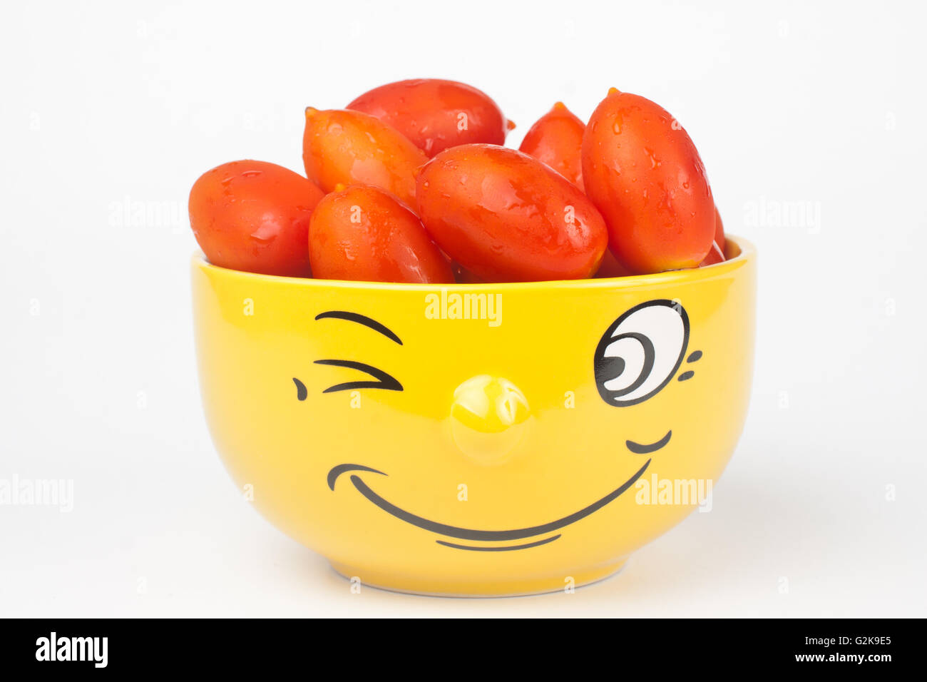 yellow smiley face bowl fullwith red cherry tomato isolated on white ...