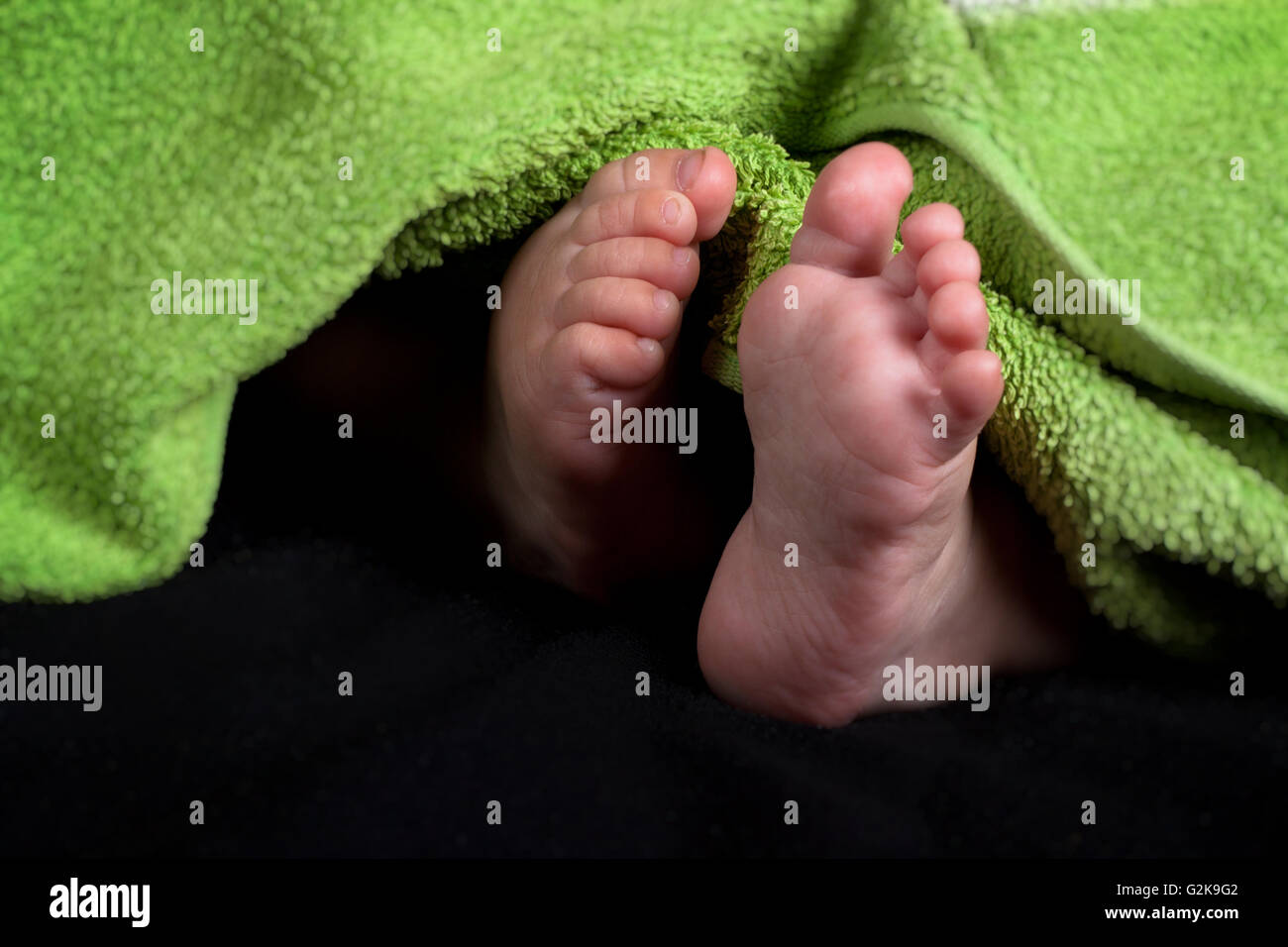 baby feet with green towel on black background Stock Photo - Alamy