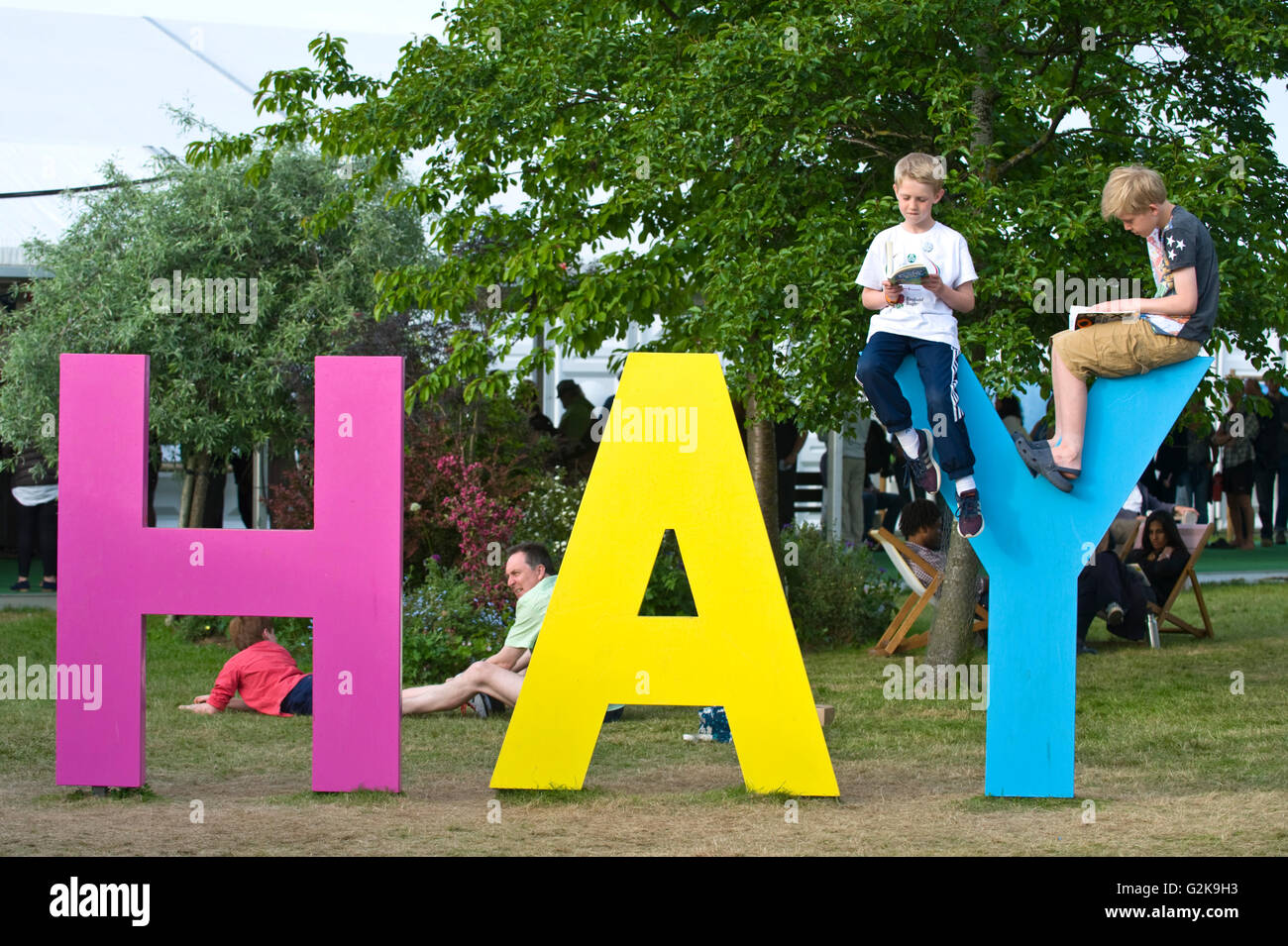 Two young boys reading books sitting on HAY sign at Hay Festival 2016 ...