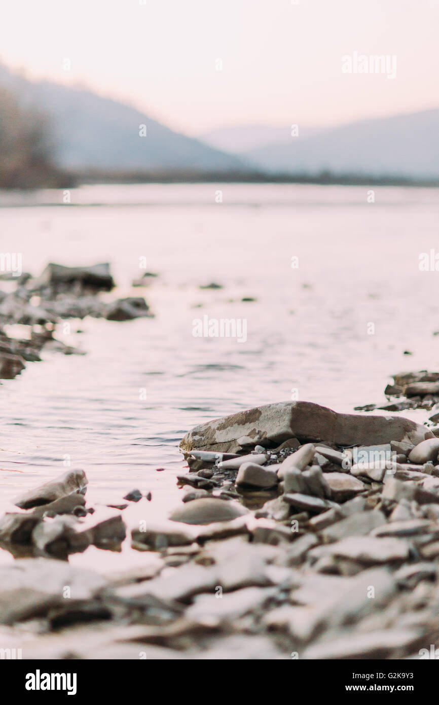 Crushed stones at pebble river bank with forest hills on background ...