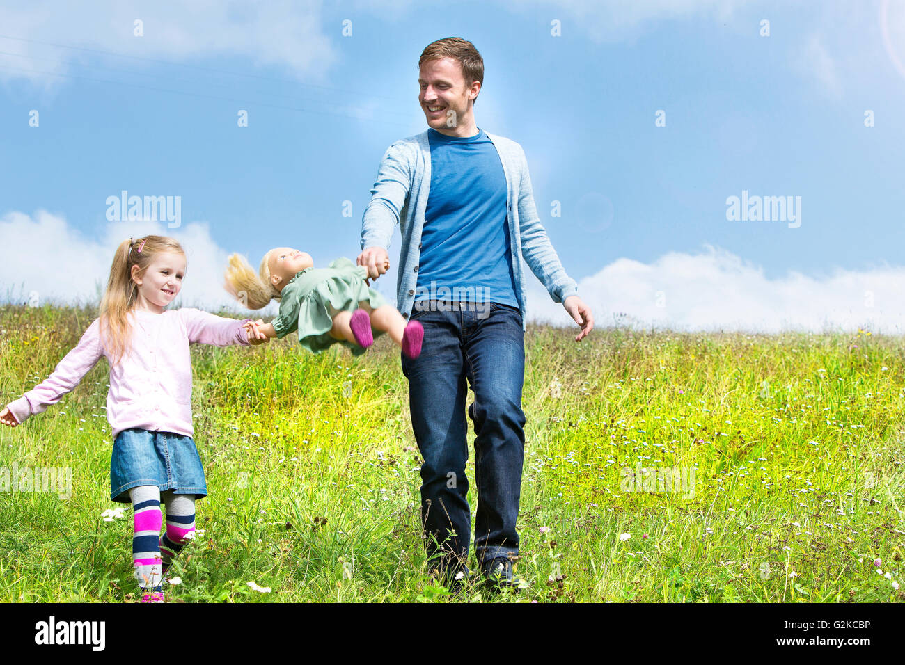 Happy father and daughter walking with doll in meadow Stock Photo - Alamy