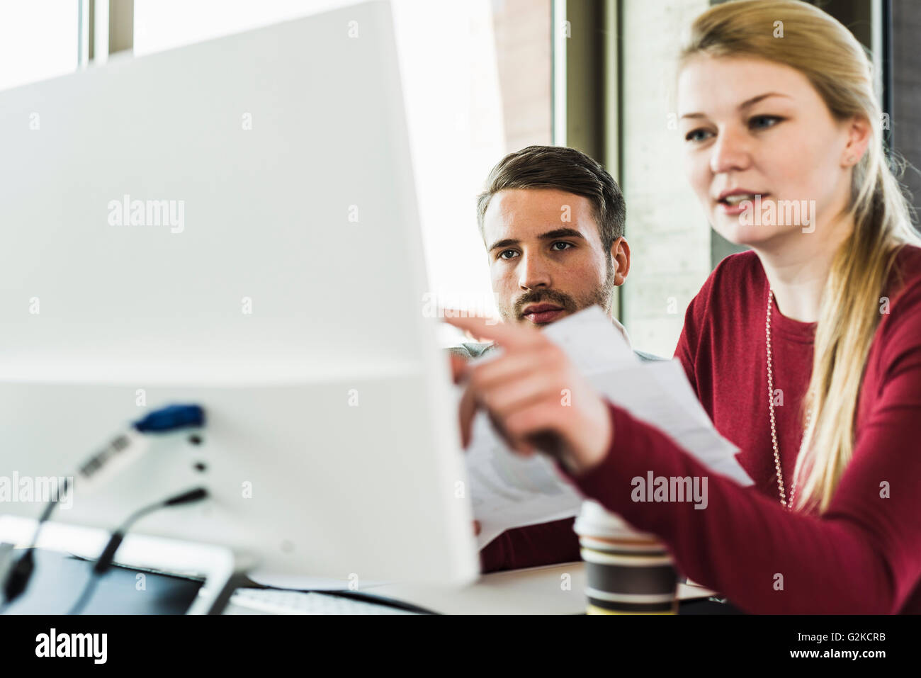 Two colleagues at office desk looking at computer monitor Stock Photo ...