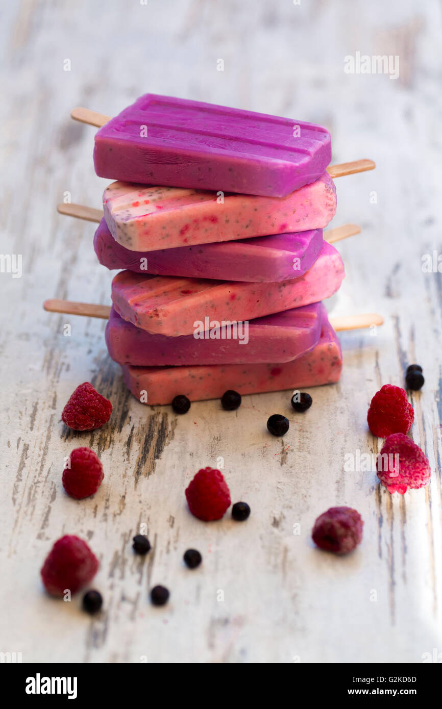 Stack of homemade blueberry ice lollies and raspberry ice lollies with ...