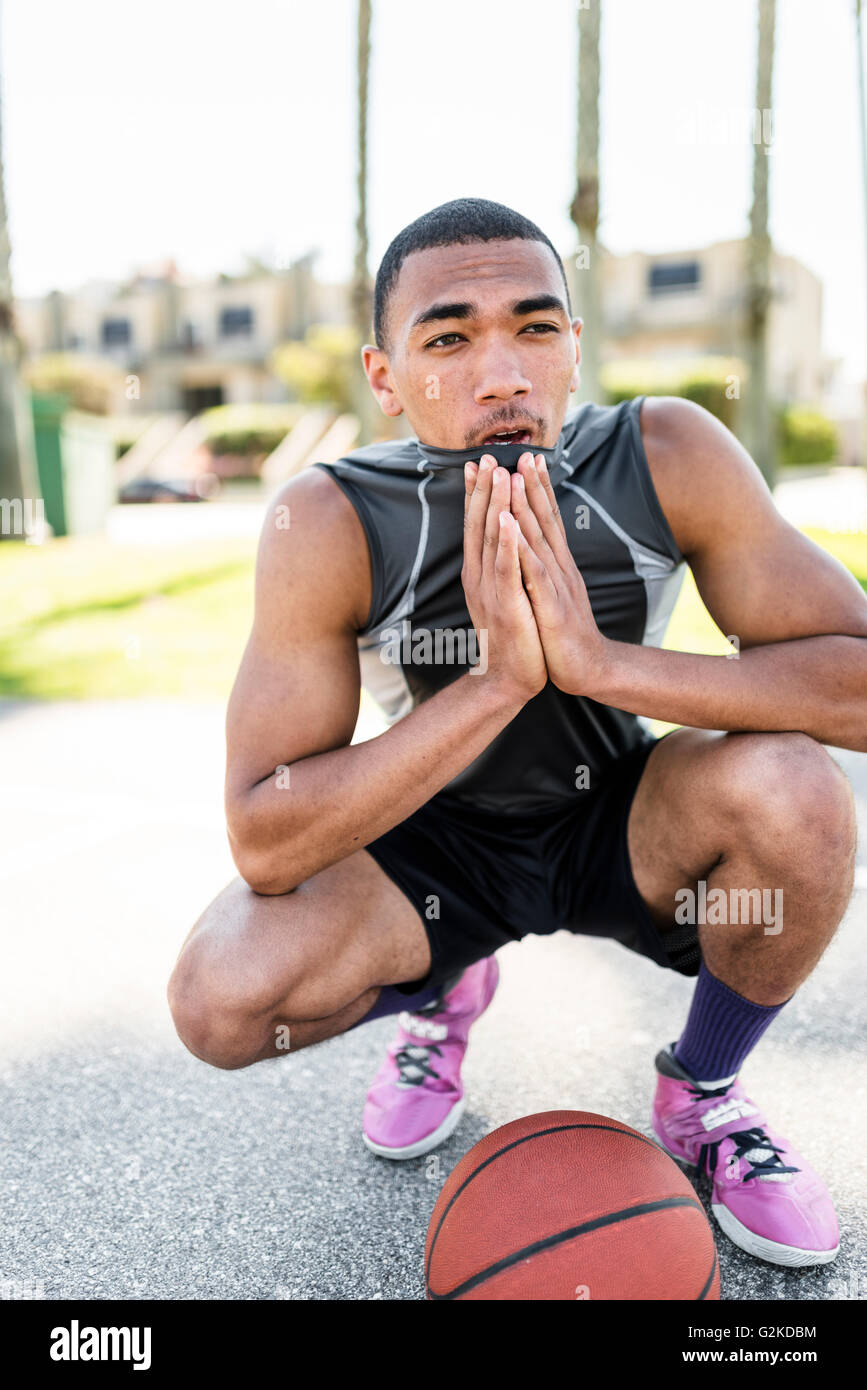 Basketball player crouching on outdoor court Stock Photo - Alamy
