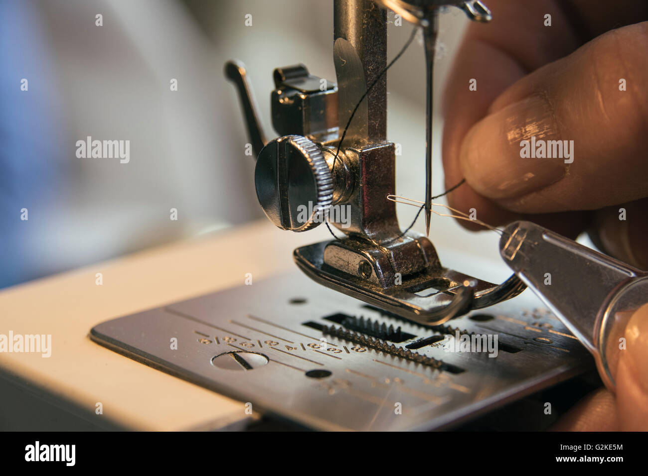 Woman adjusting thread in a sewing machine Stock Photo - Alamy