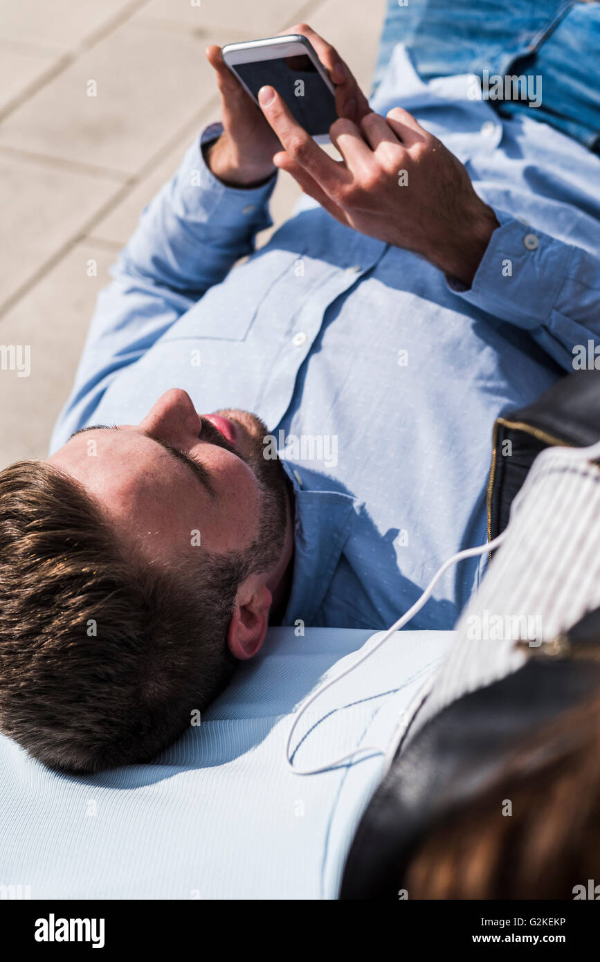 Young man lying on bench using smart phone Stock Photo - Alamy