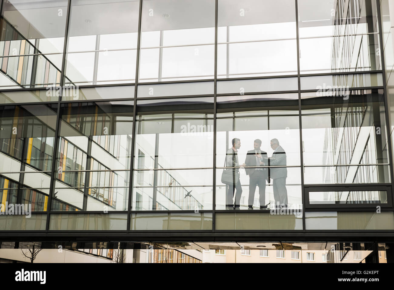 Three businessmen behind glass facade Stock Photo - Alamy