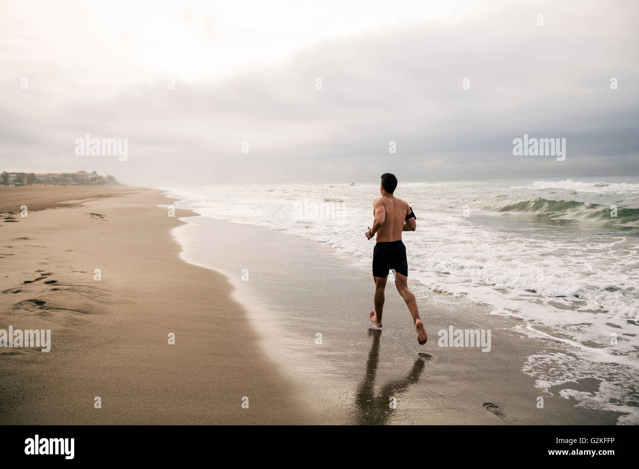 Young man running on the beach Stock Photo - Alamy