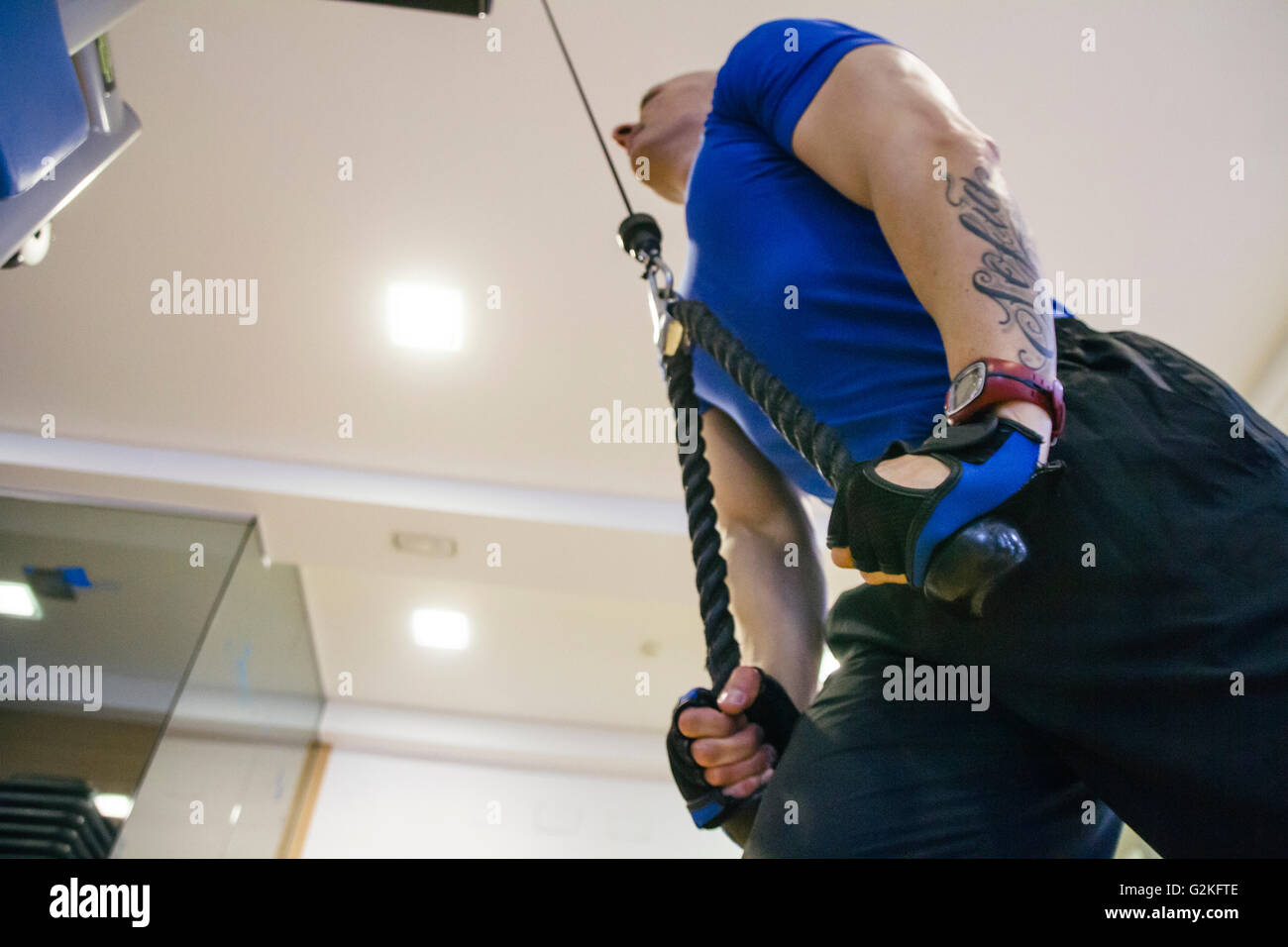 Man doing tricep extensions on high pulley Stock Photo - Alamy