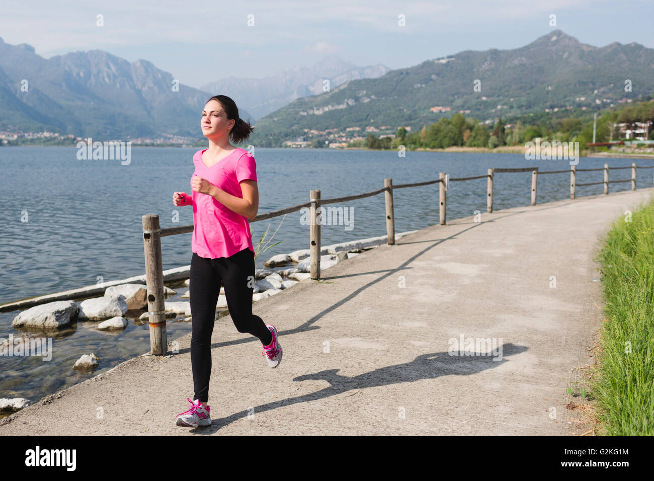 Italy, Lecco, young woman running along the lake Stock Photo - Alamy