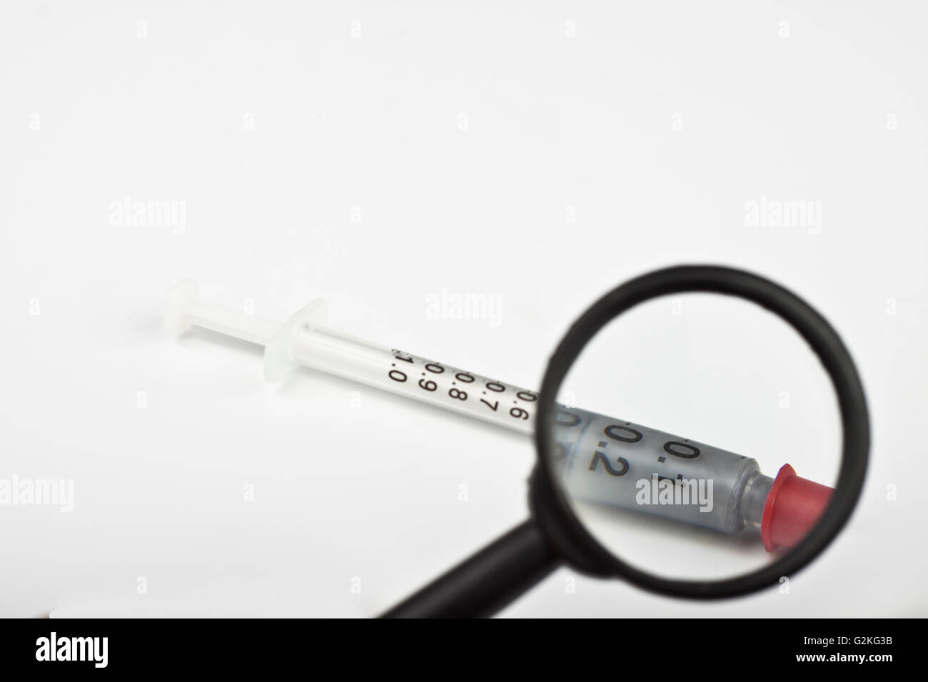 syringe with a magnifying glass on white background Stock Photo - Alamy