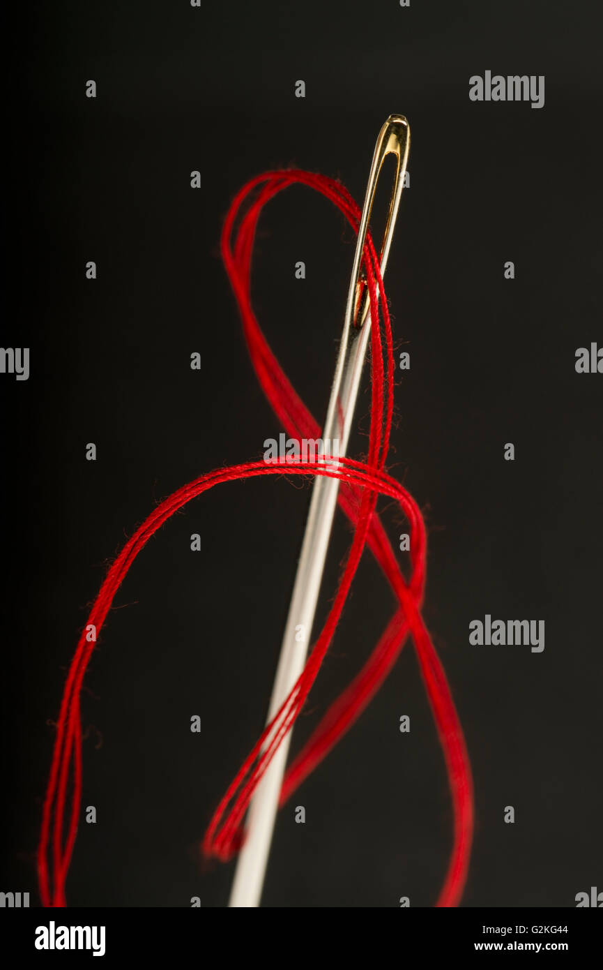 Red thread pulled through needle's eye Stock Photo - Alamy