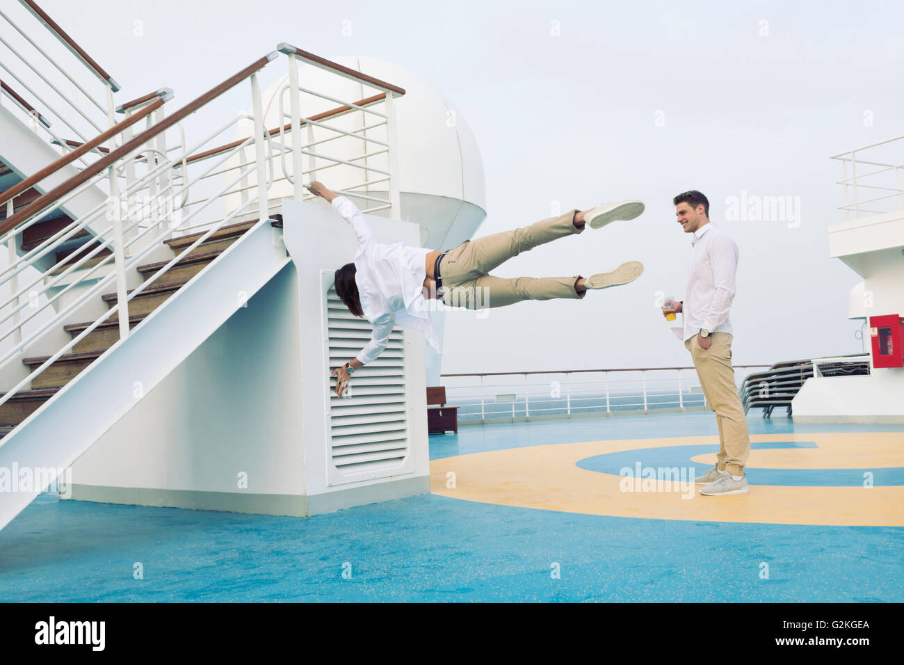 Two young men messing about on cruise ship, doing gymnastics Stock ...