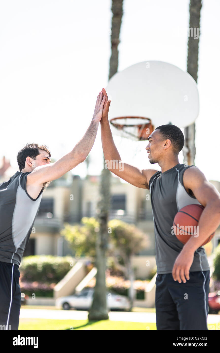 Two young men high-fiving on outdoor basketball court Stock Photo - Alamy