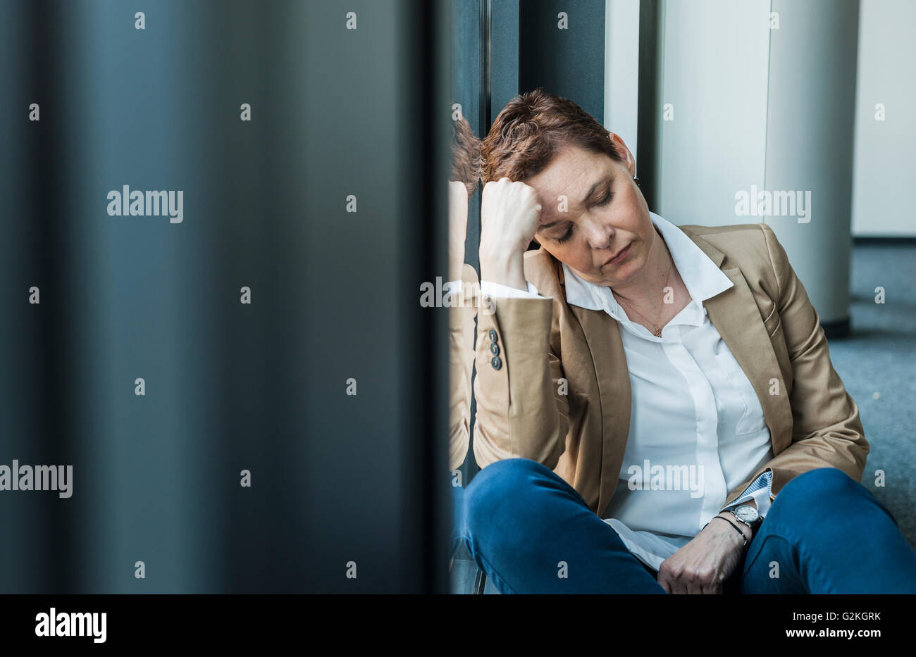 Tired female senior manager sitting on window, eyes closed Stock Photo ...