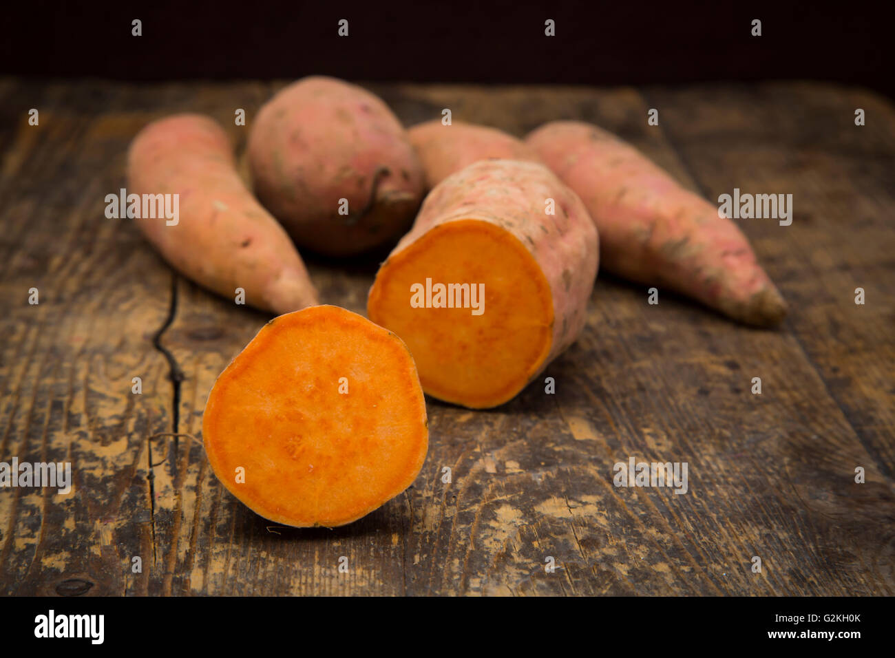 Sliced and whole sweet potatoes on dark wood Stock Photo - Alamy